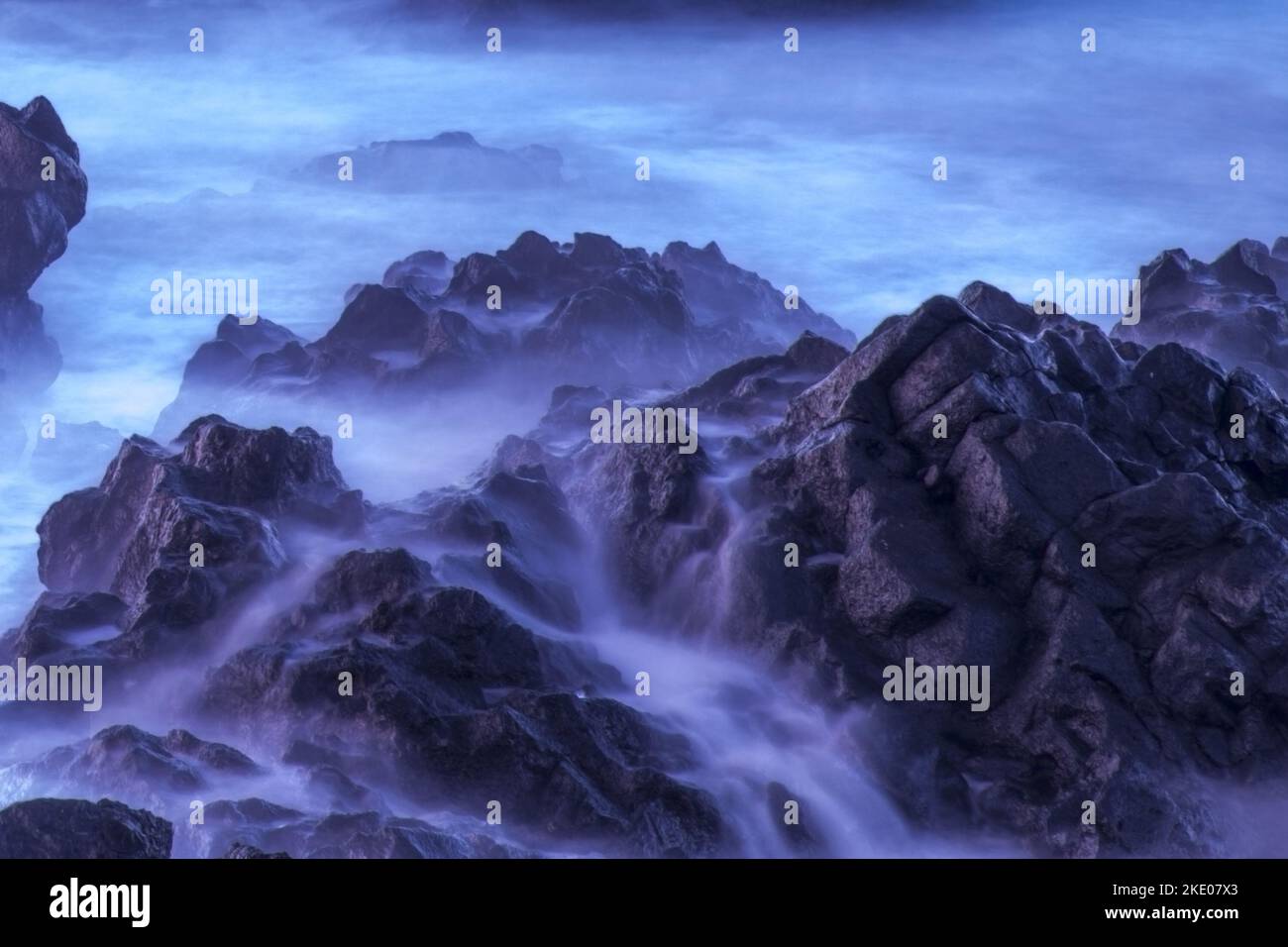 A long exposure of fog, mist on rocks, a purple background Stock Photo ...