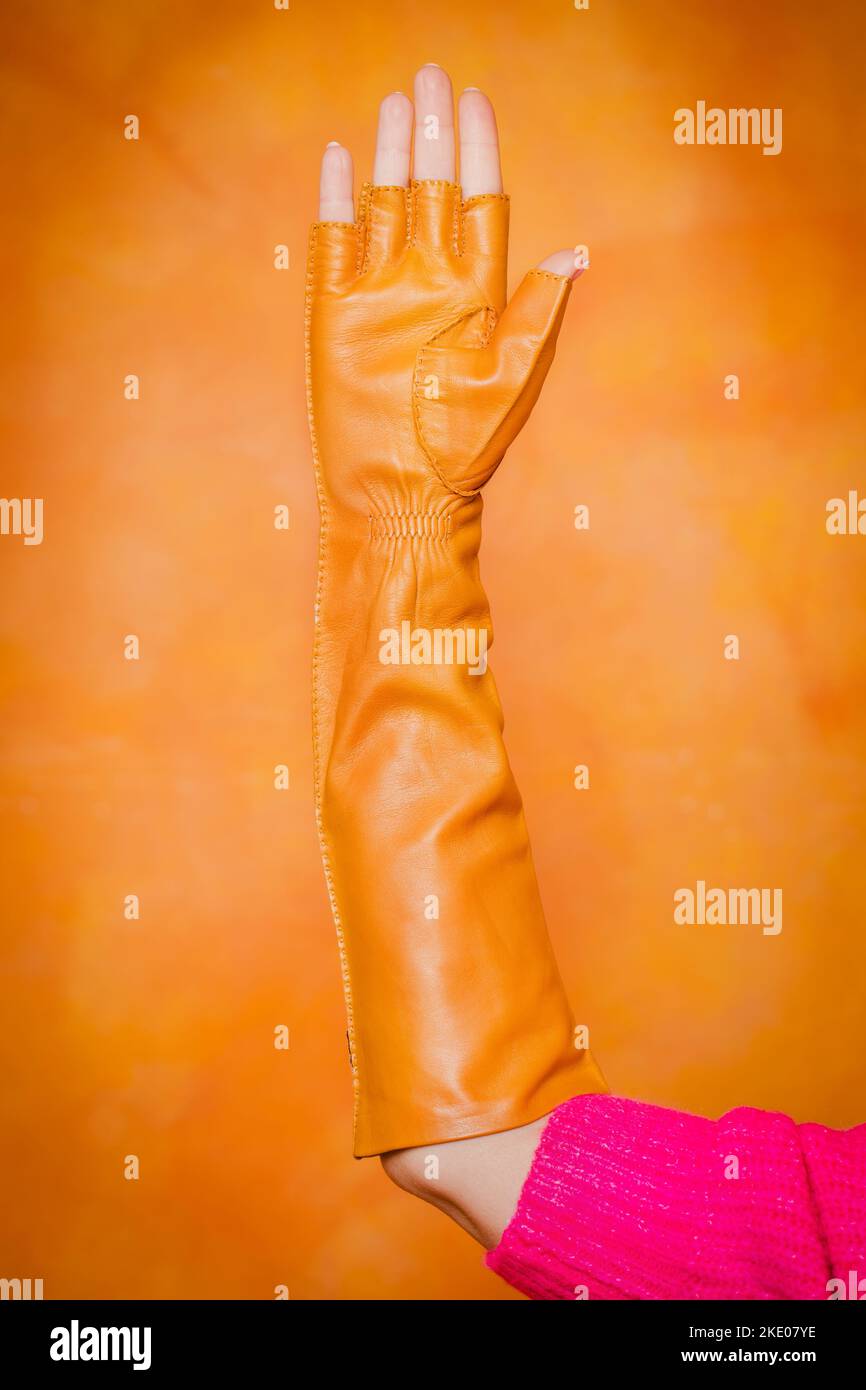 Yellow long mitten gloves on a woman's hand on an orange background ...