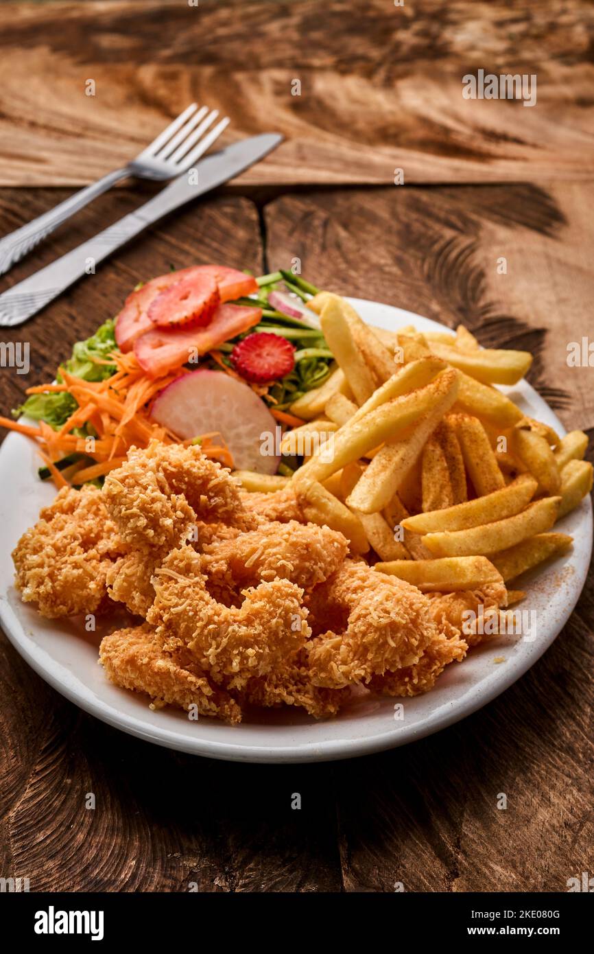 A vertical shot of deep-fried shrimp, potatoes, and vegetables on a ...