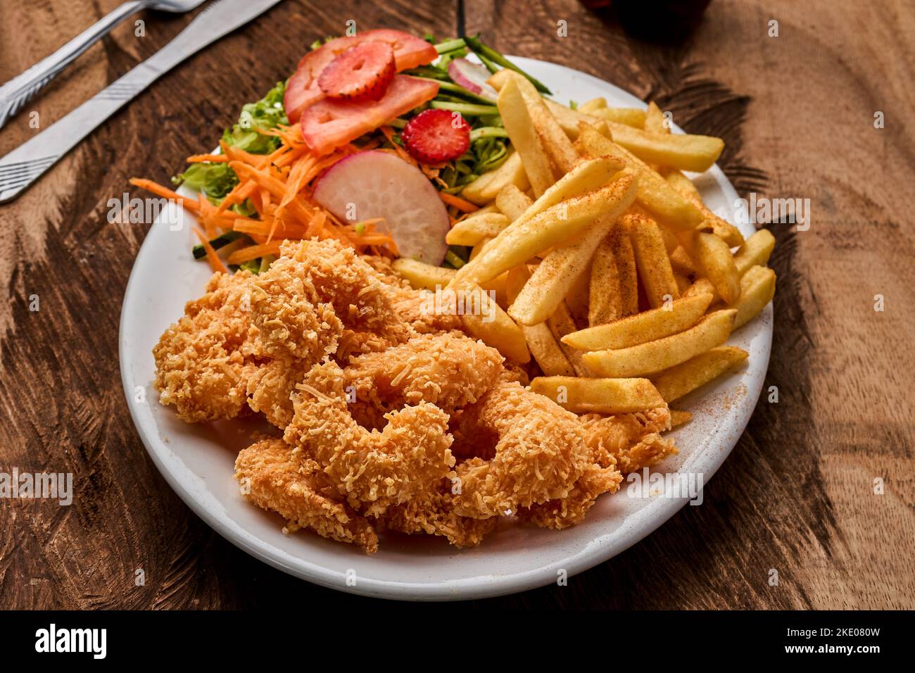 A top view of deep-fried shrimp, potatoes, and vegetables on a white ...