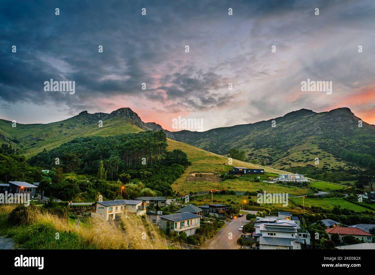 A small village in front of high mountains covered in forests at sunset ...