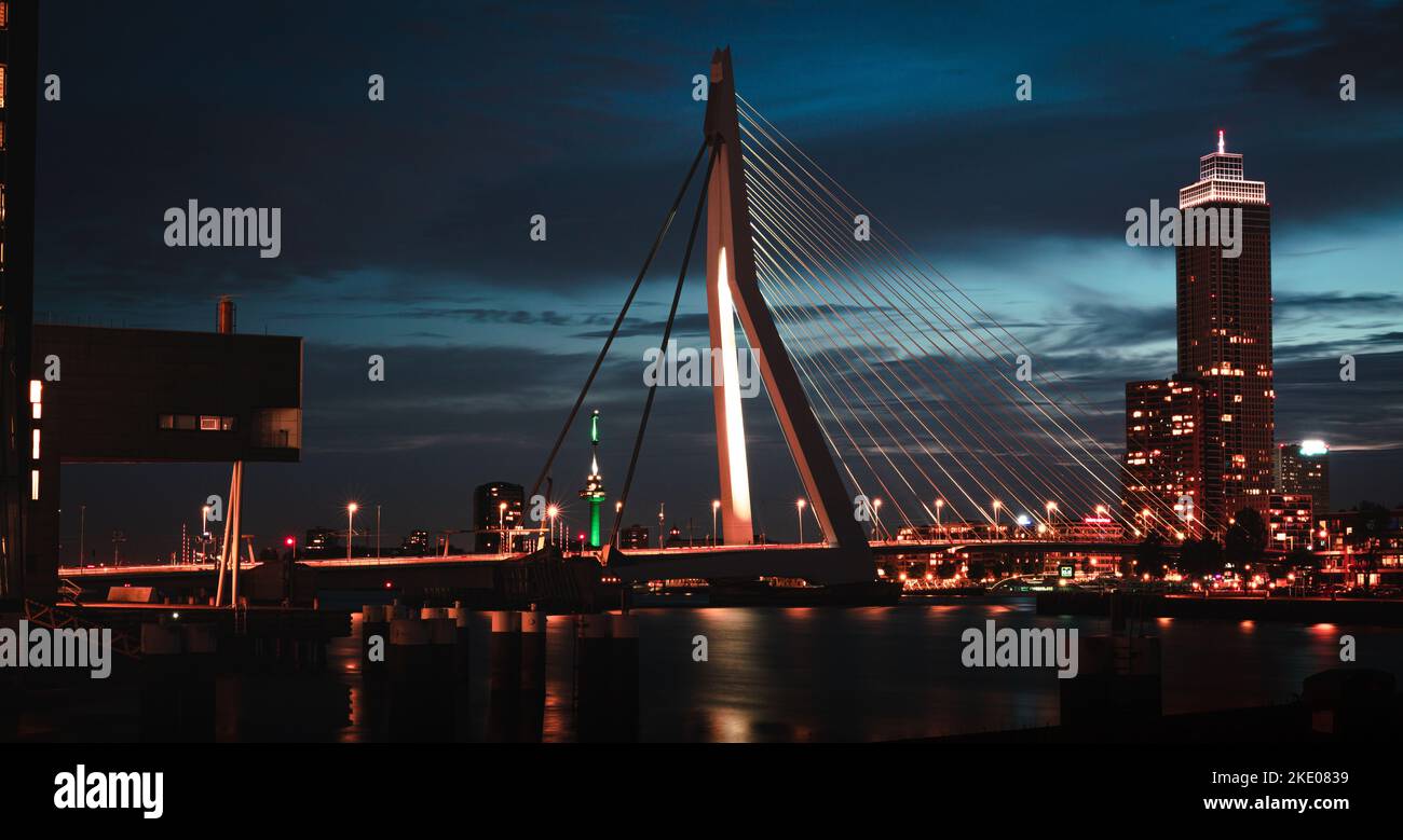 A view of the Erasmusbrug bridge and illuminated city buildings at ...