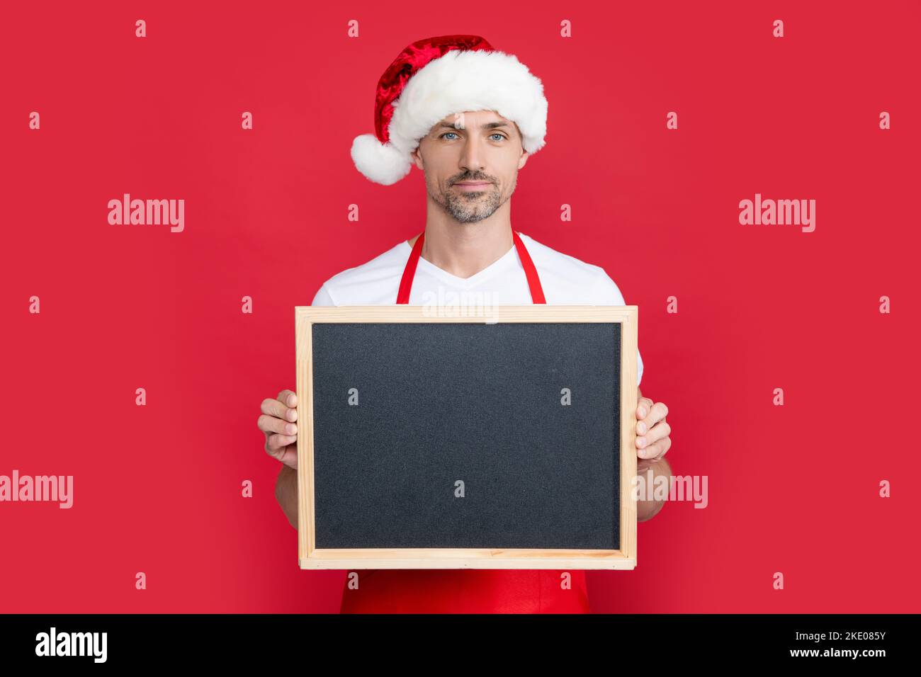 mature man in new year hat and red apron hold blackboard with copy ...
