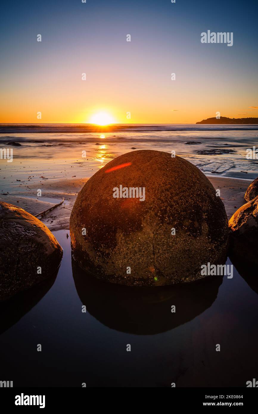 A vertical of Moeraki Boulders Beach in Hampden, New Zealand at sunset ...