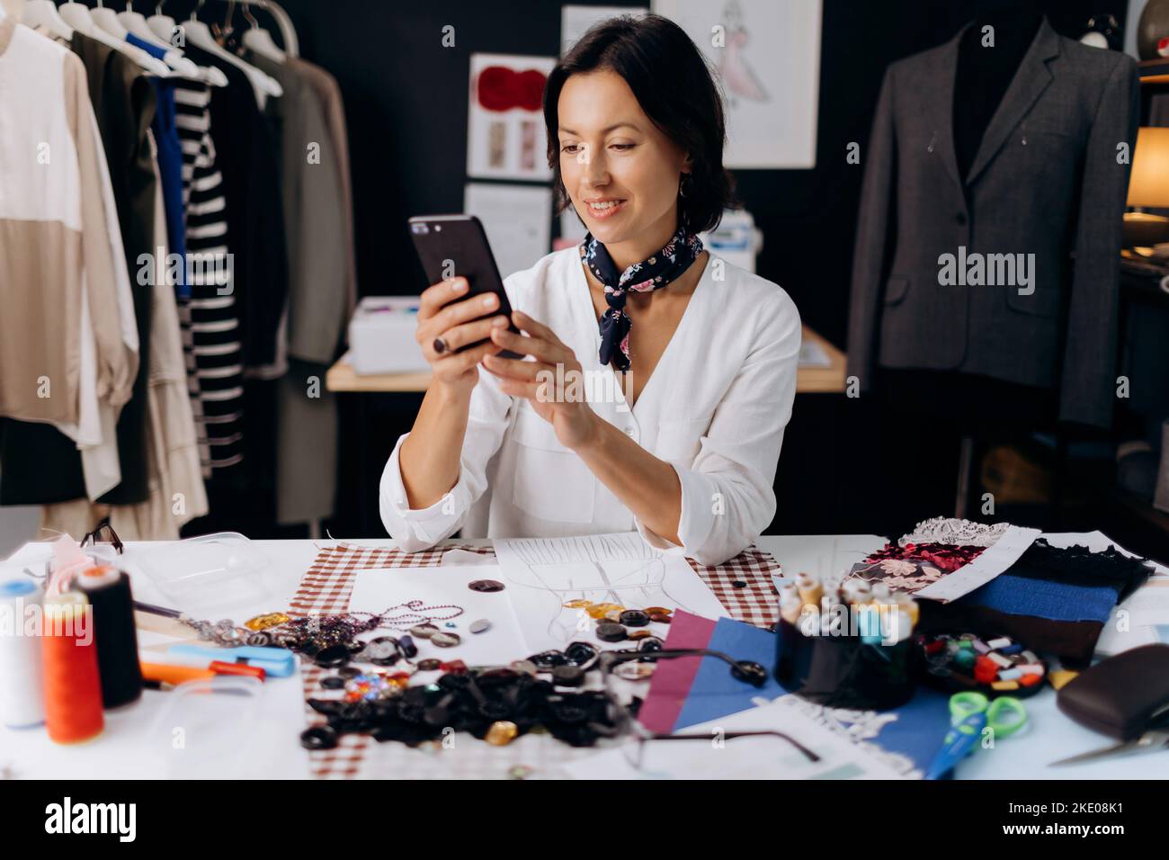 Seamstress using smartphone at work Stock Photo - Alamy