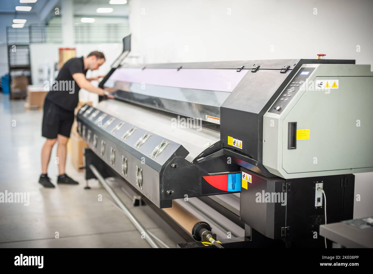 In the printing house, an experienced technician works on a UV printer ...