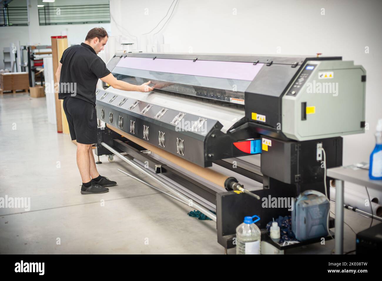 In the printing house, an experienced technician works on a UV printer ...