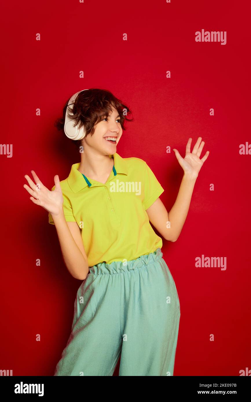 Portrait of cheerful teen girl with curly brown short hair posing in ...