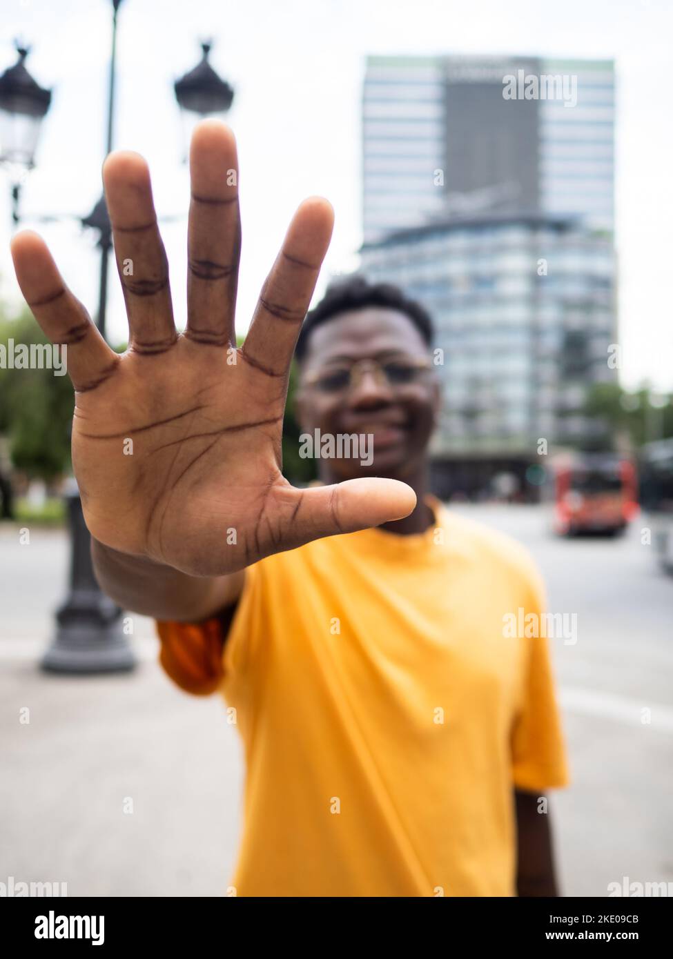 A closeup of man hand wearing yellow t-shirt standing in front of glass ...