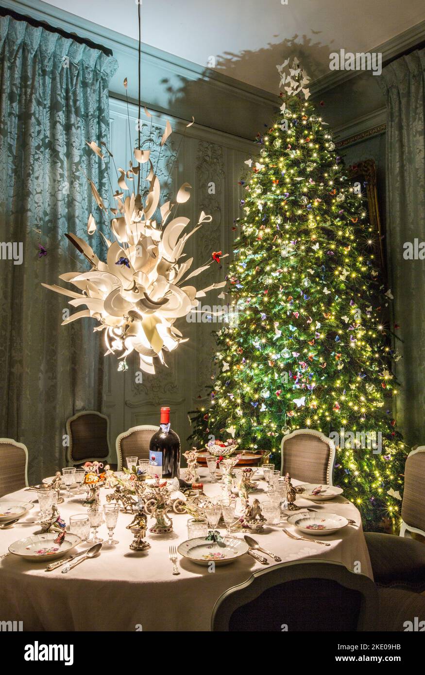 A vertical shot of a Christmas tree near a table set for dinner in ...