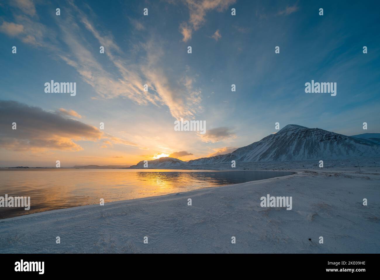 A beautiful view of a lake with snowy field and mountain during orange ...
