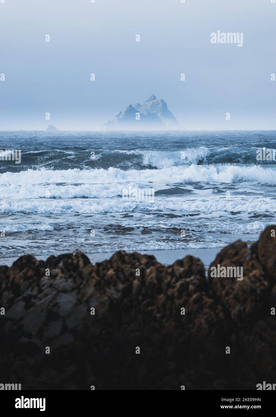 A beautiful view of a sea with big waves and a mountain in a background ...