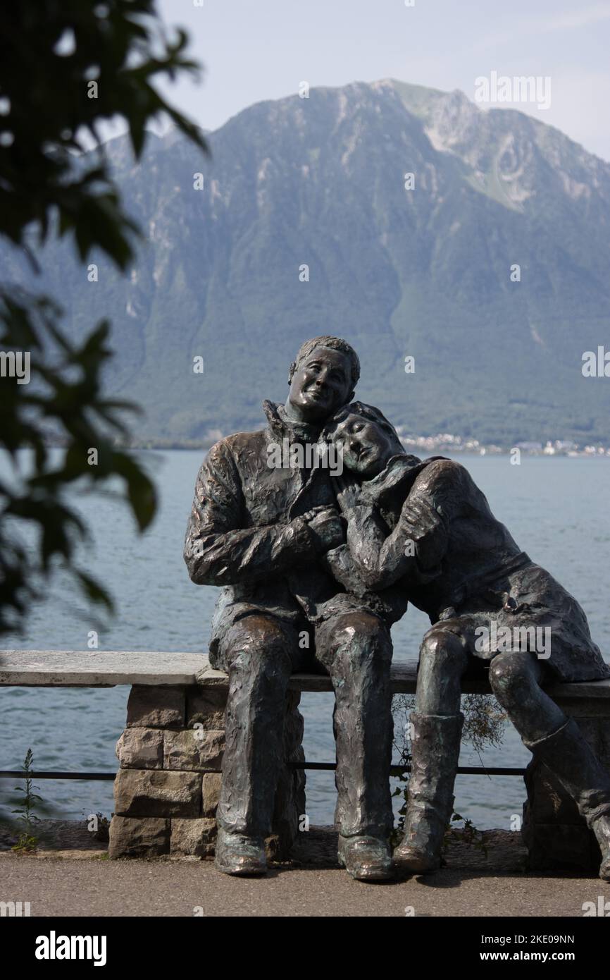The vertical view of a loving couple statue on the bench before the sea ...