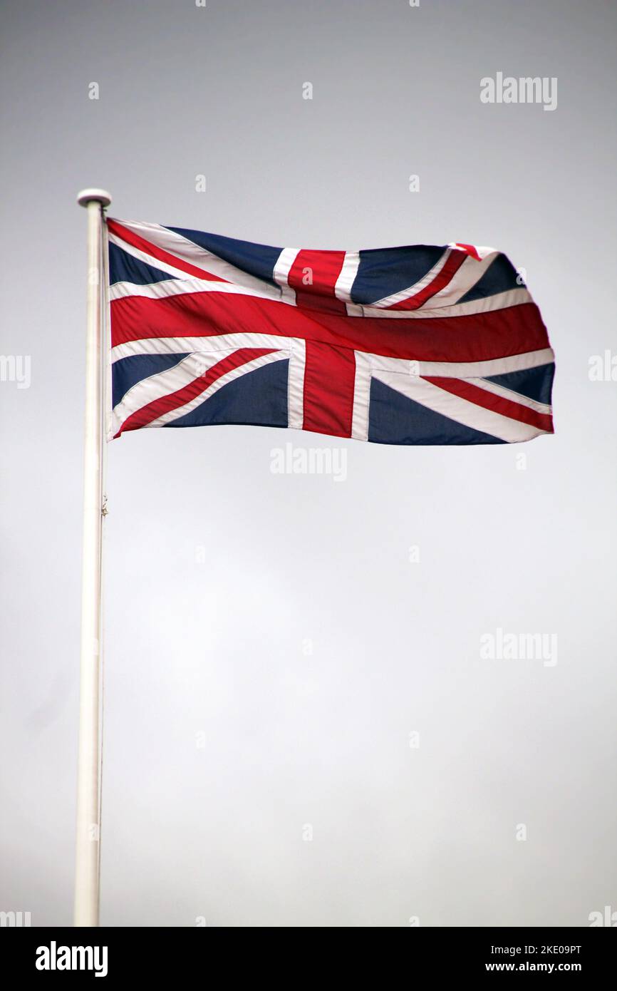 A vertical shot of the United Kingdom flag on a high pole waving in the ...