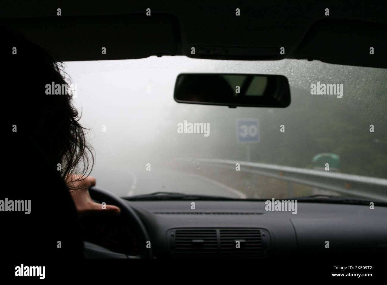 A person driving a car with a black interior in the rain and foggy ...