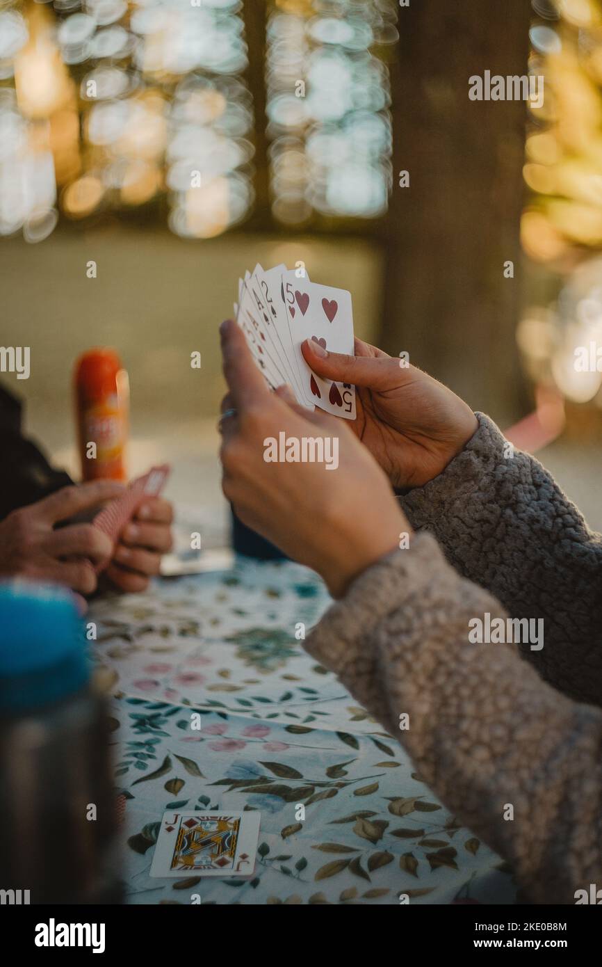 Two people playing cards in a forest while camping outside at a picnic ...
