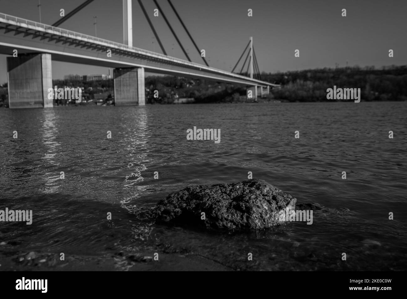 A grayscale of a landscape with a bridge over a river Stock Photo - Alamy