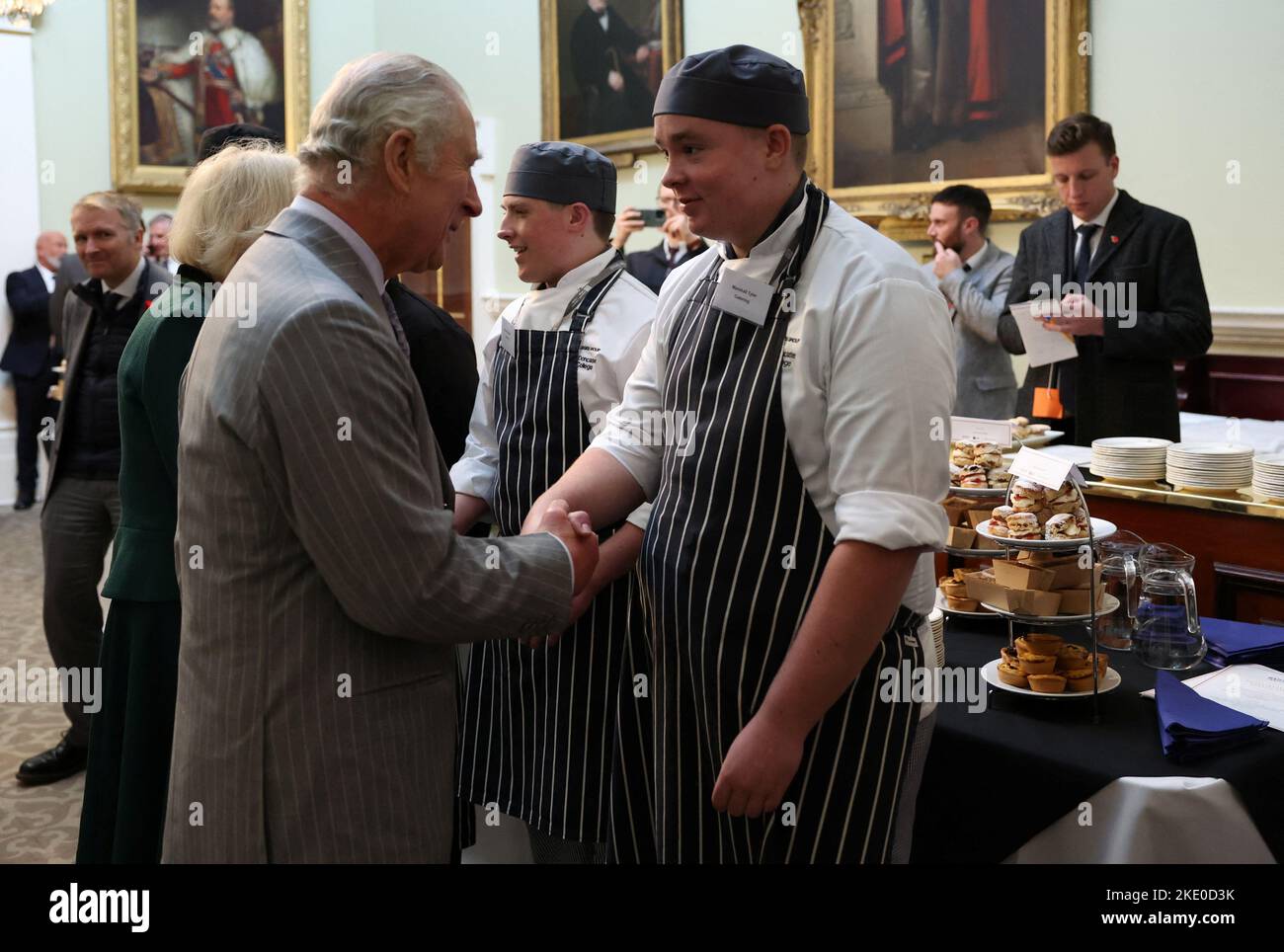 King Charles III and the Queen Consort speak to staff during a ceremony ...