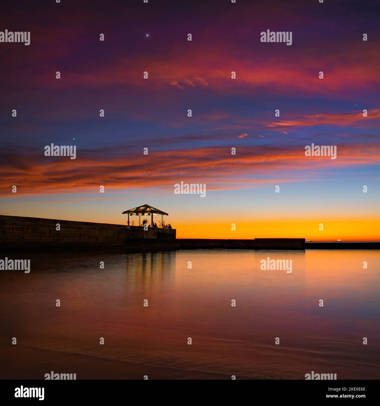 A boardwalk with a cabin on the beach at sunset with a gorgeous ...