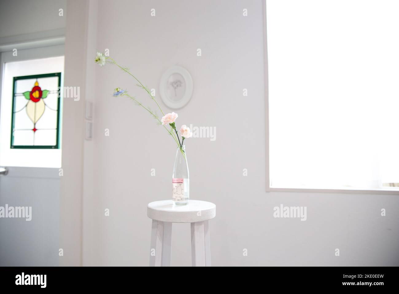 The cute little flowers in a glass vase on a white stool isolated in a ...