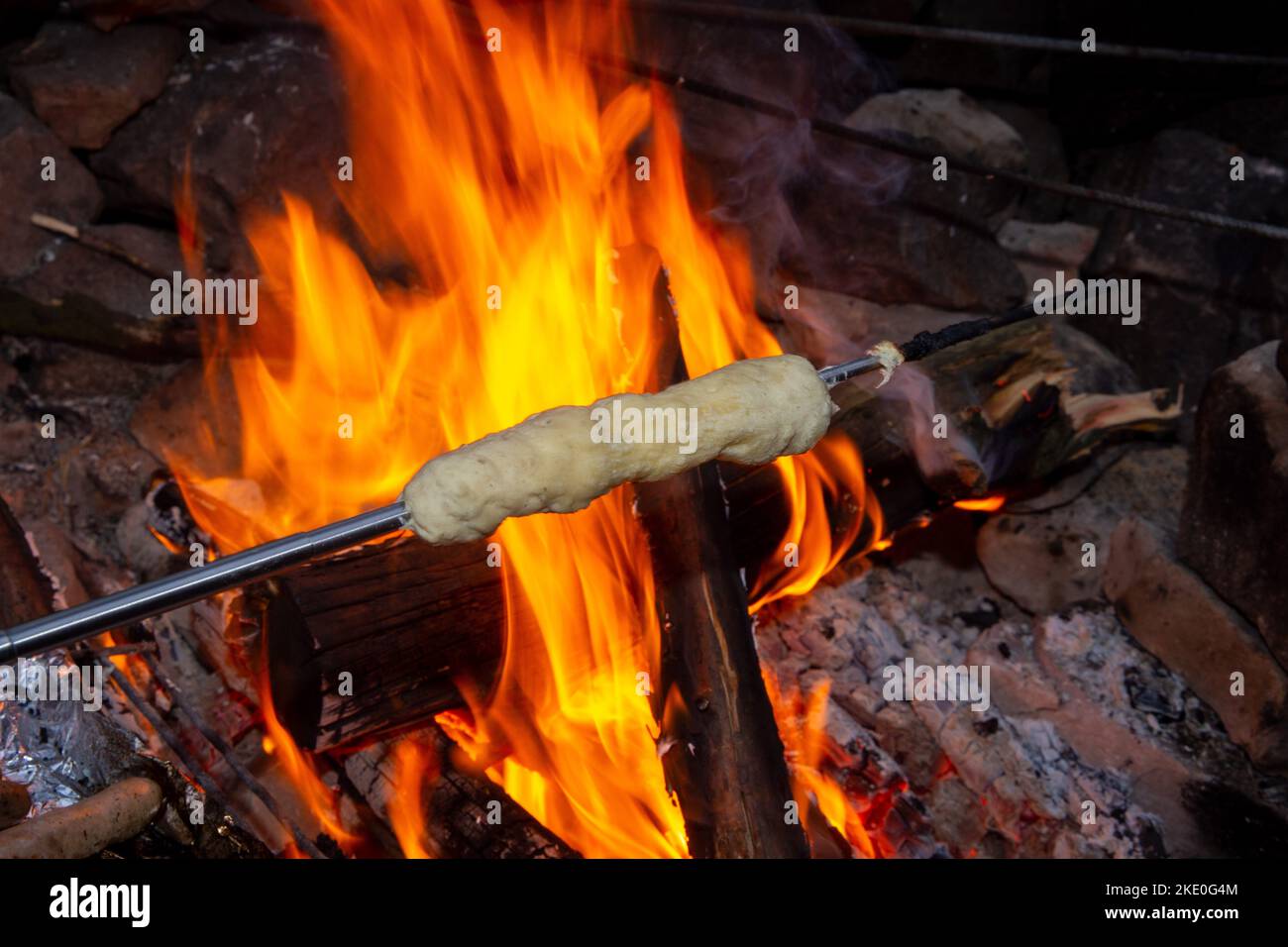 Baking of stick bread on the camp fire Stock Photo - Alamy