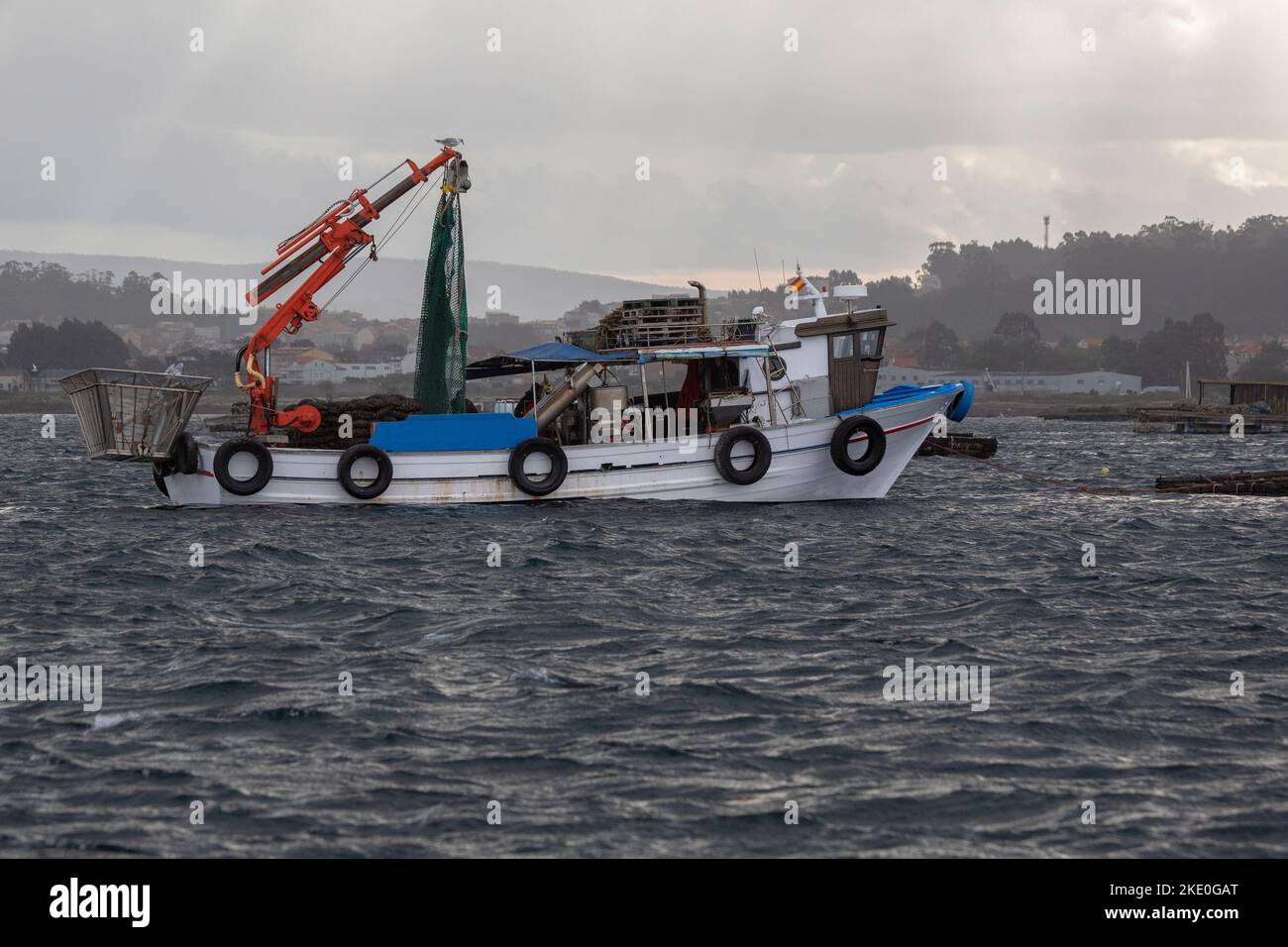 Traditional wooden fishing boat working in the mussel farming rafts of ...
