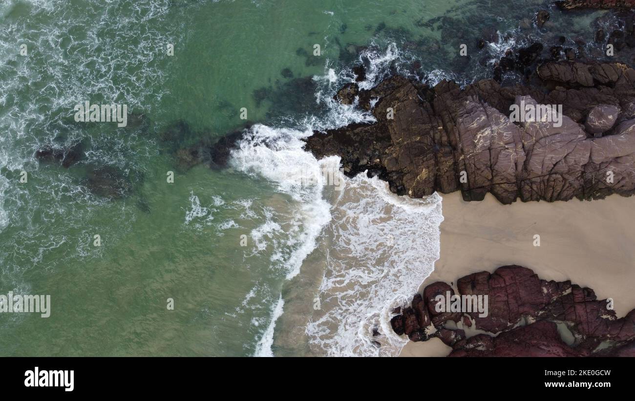A top view of high black cliffs and wavy water streams washing over the ...