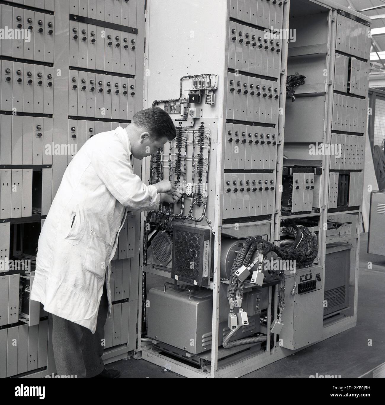 1950s, historical, white coated engineer working on an electrical ...