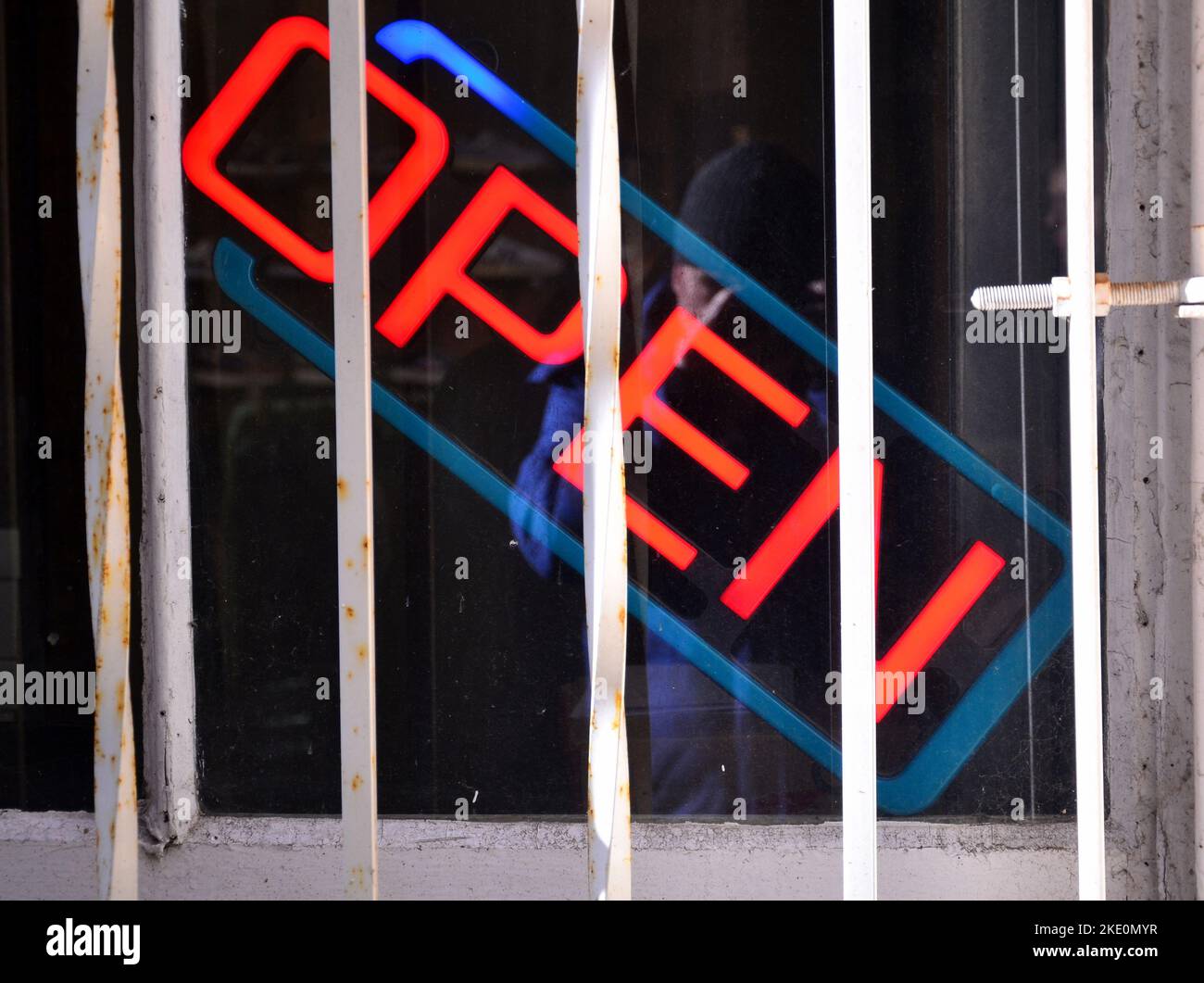 Exterior illuminated sign says open behind security bars in central ...