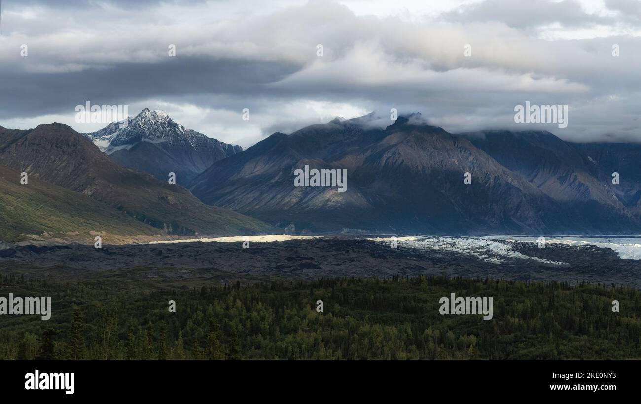 A scenic shot of a high mountain range with snowy peaks under the ...