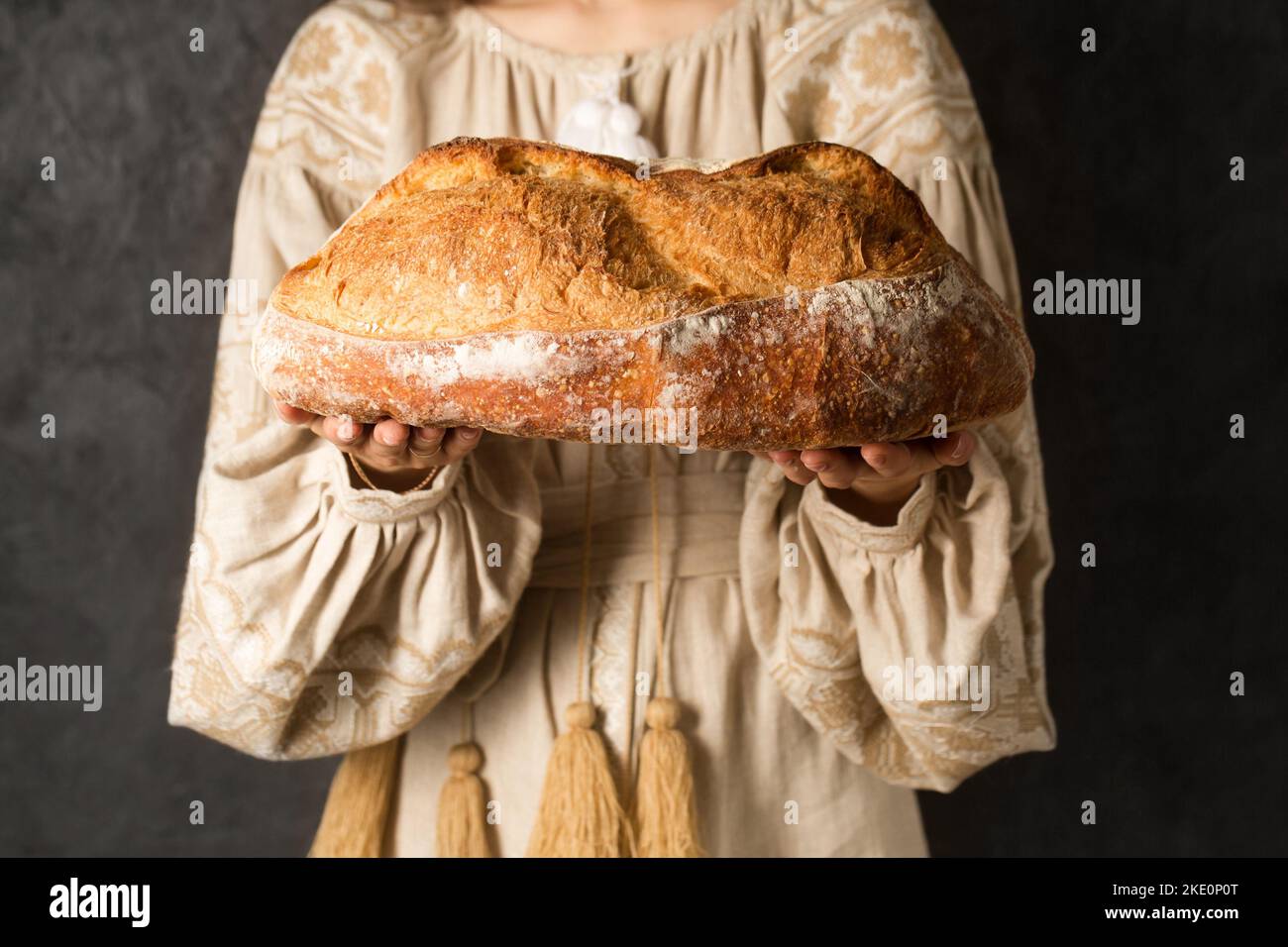 A Ukrainian woman in national dress holds a huge loaf of bread in her ...