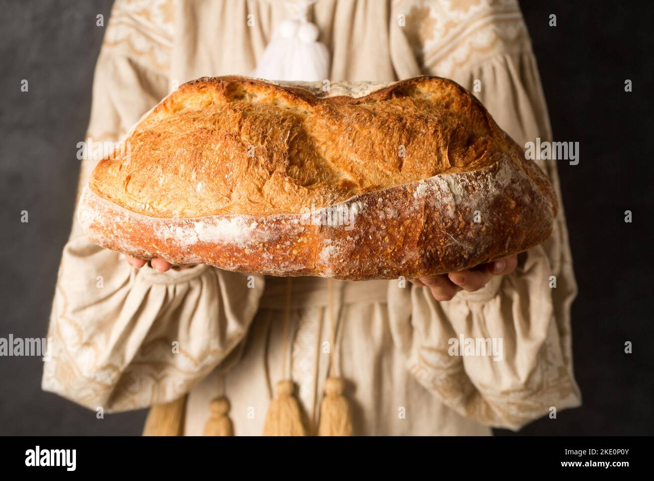 A Ukrainian woman in national dress holds a huge loaf of bread in her ...
