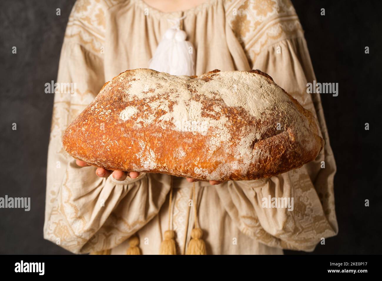 A Ukrainian woman in national dress holds a huge loaf of bread in her ...