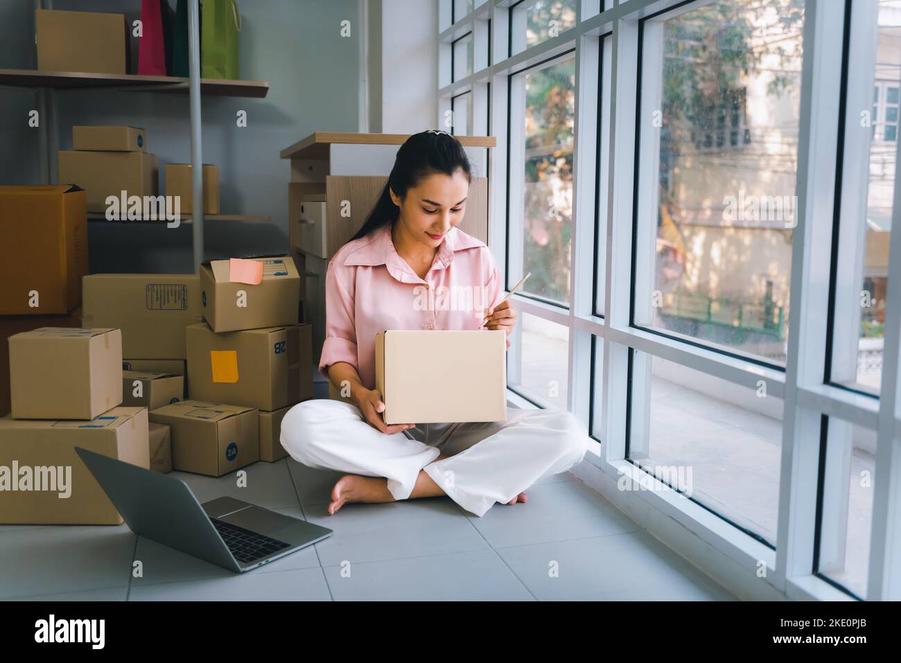 Asian woman writing customer address on the parcel for delivery, Online ...