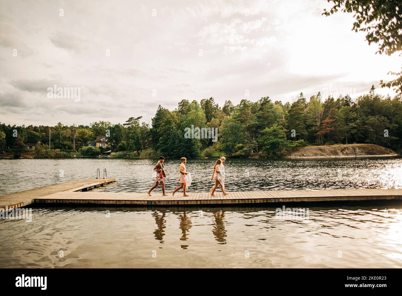 Friends walking on jetty at lake during vacation Stock Photo - Alamy