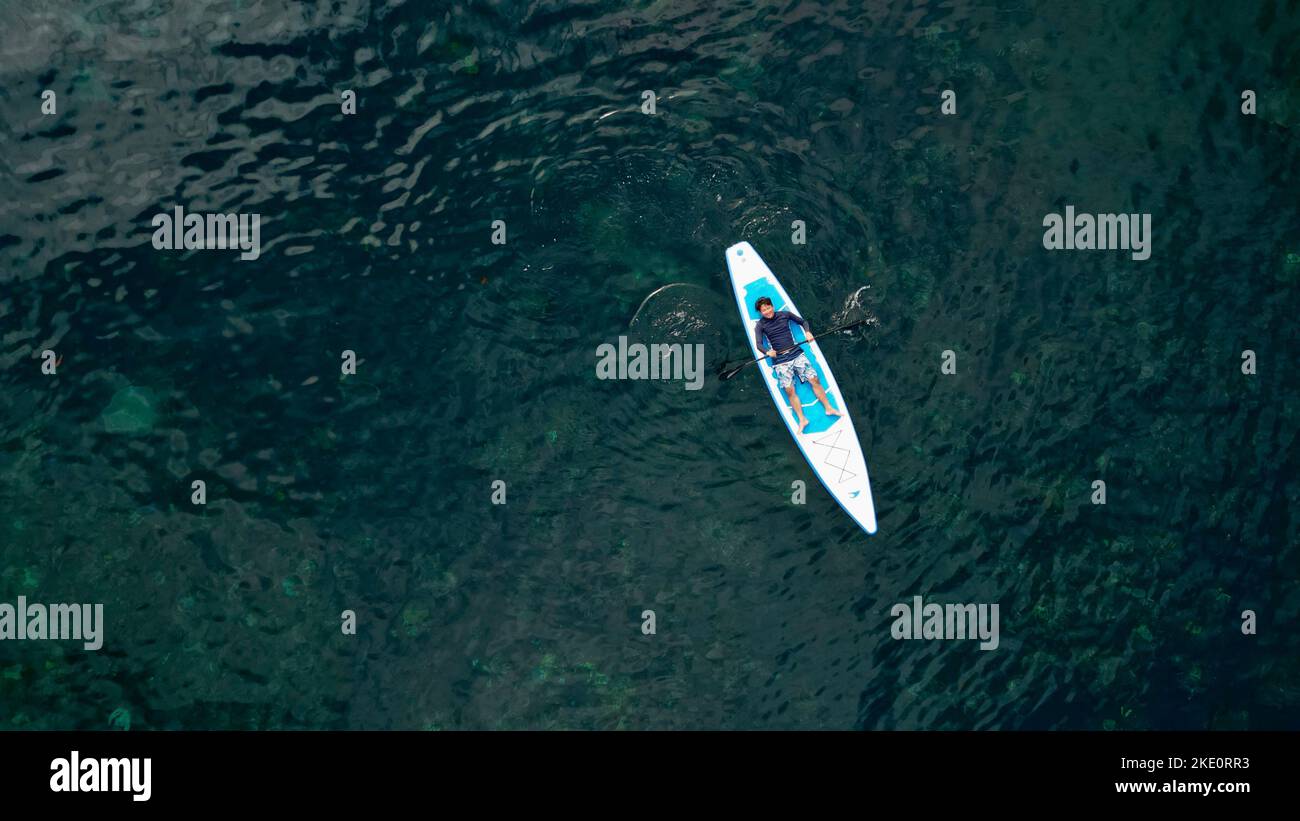 An aerial view of a person in a kayak floating on the water in Bali ...