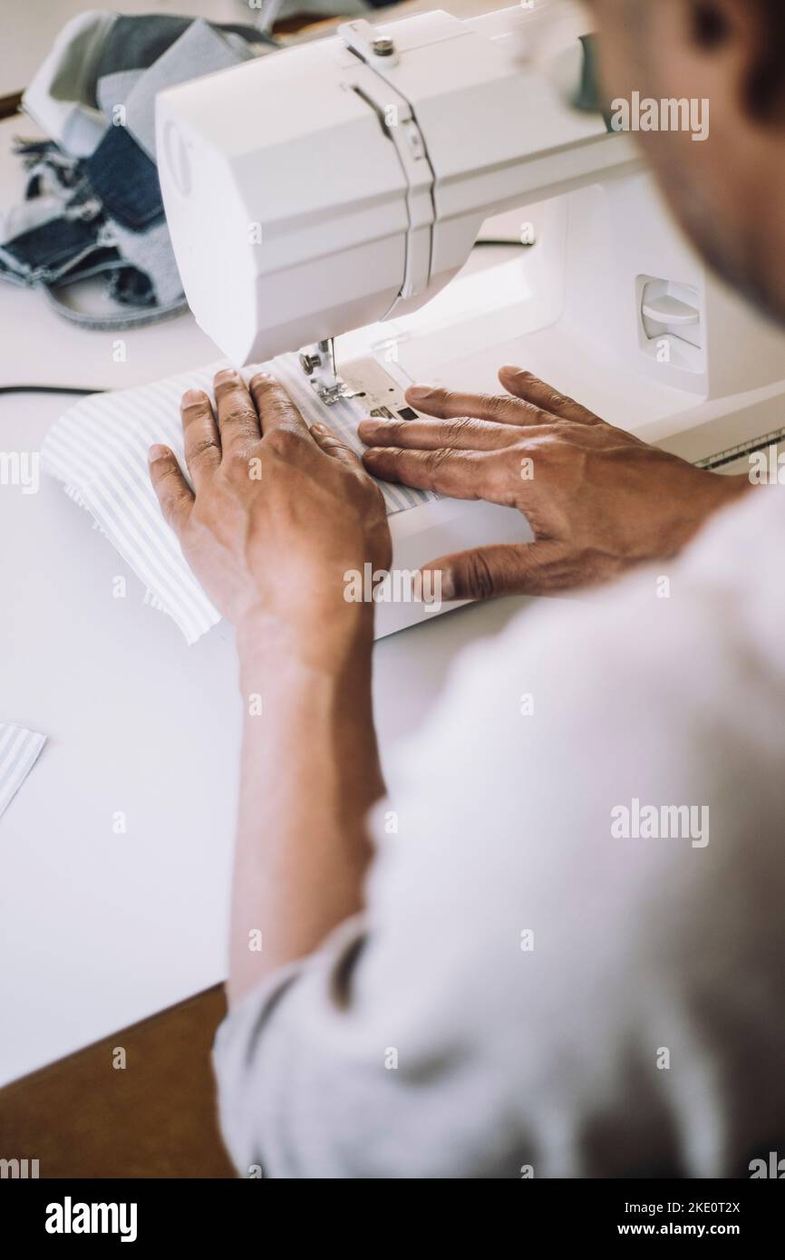 Male fashion designer sewing cloth using sewing machine while working ...