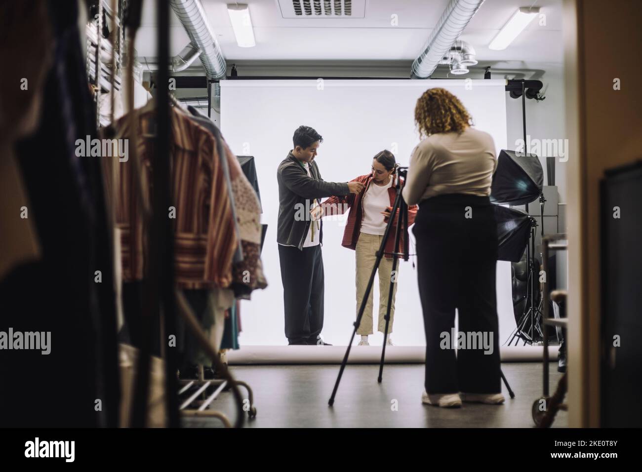 Male design professional assisting fashion model during photo shoot in ...