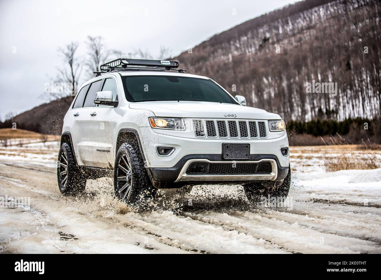 The white Jeep Grand Cherokee car driving through the snow Stock Photo ...