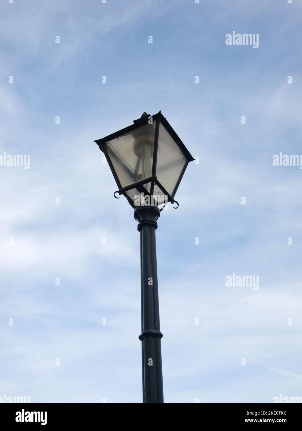 A vertical shot of an old street light on blue cloudy sky background ...