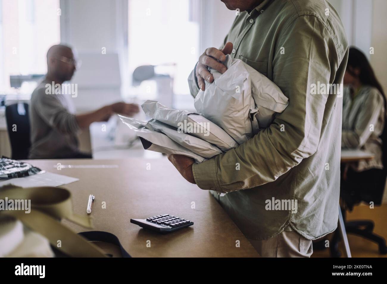 Midsection of male design professional examining packages at workshop ...