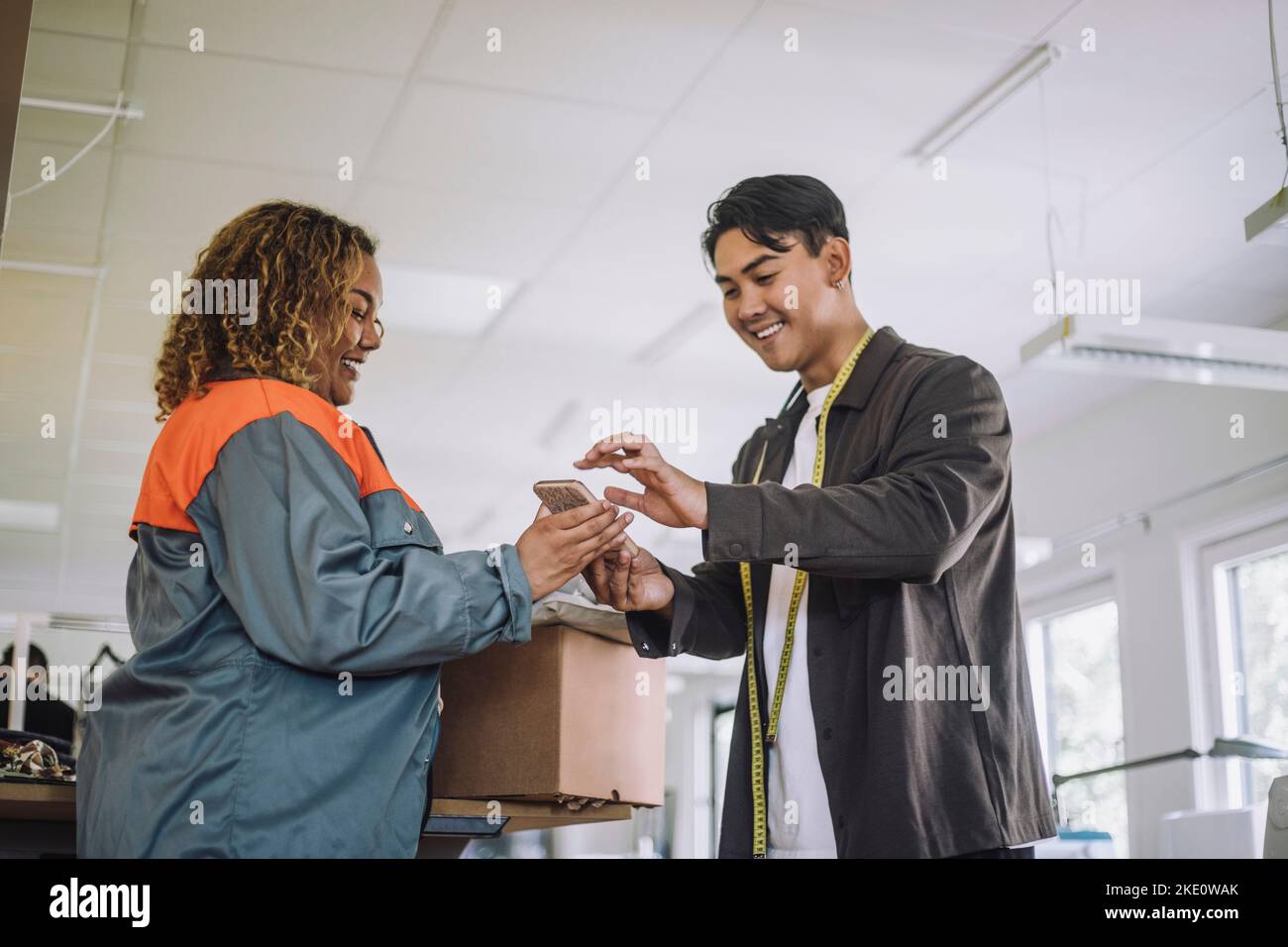 Smiling male fashion designer giving digital signature while receiving ...