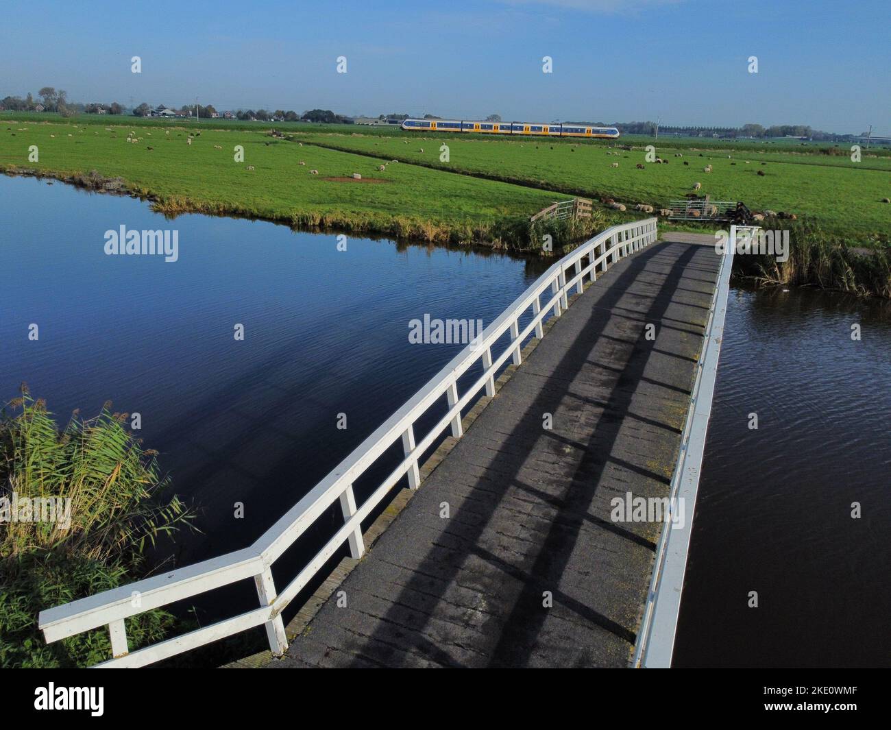 A scenic view of an old wooden bridge built above the river in a rural ...