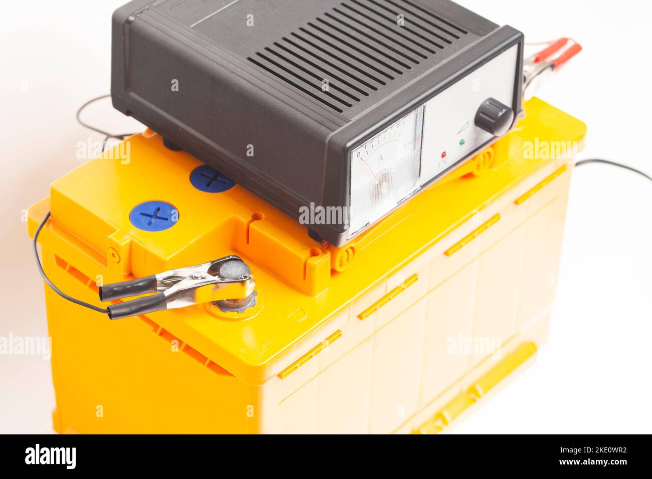 yellow car battery with car battery charger isolated on white ...