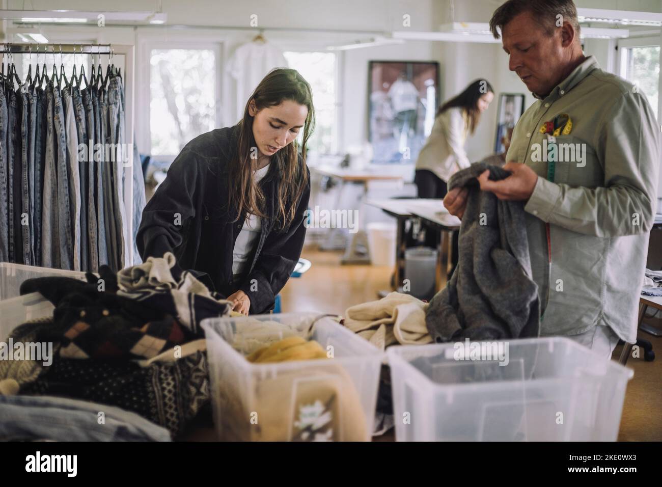 Female fashion designer with male colleague sorting recycled clothes ...