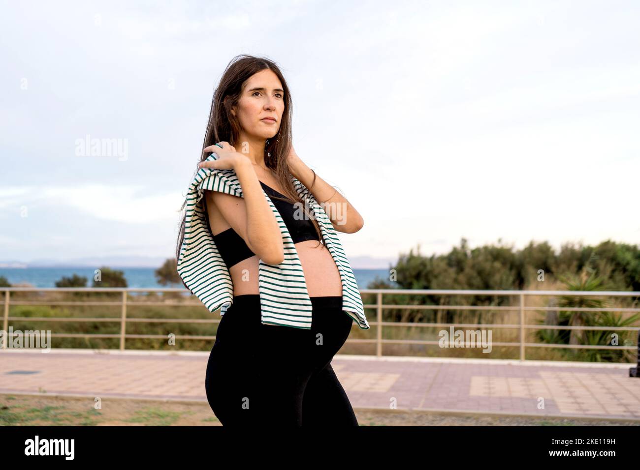 pregnant young woman with long brown hair wears sportswear and does ...