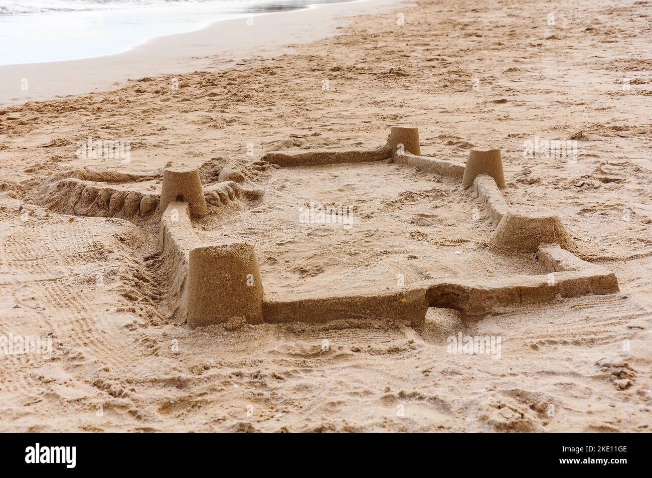 Sandcastle with a wall and towers on the beach Stock Photo - Alamy