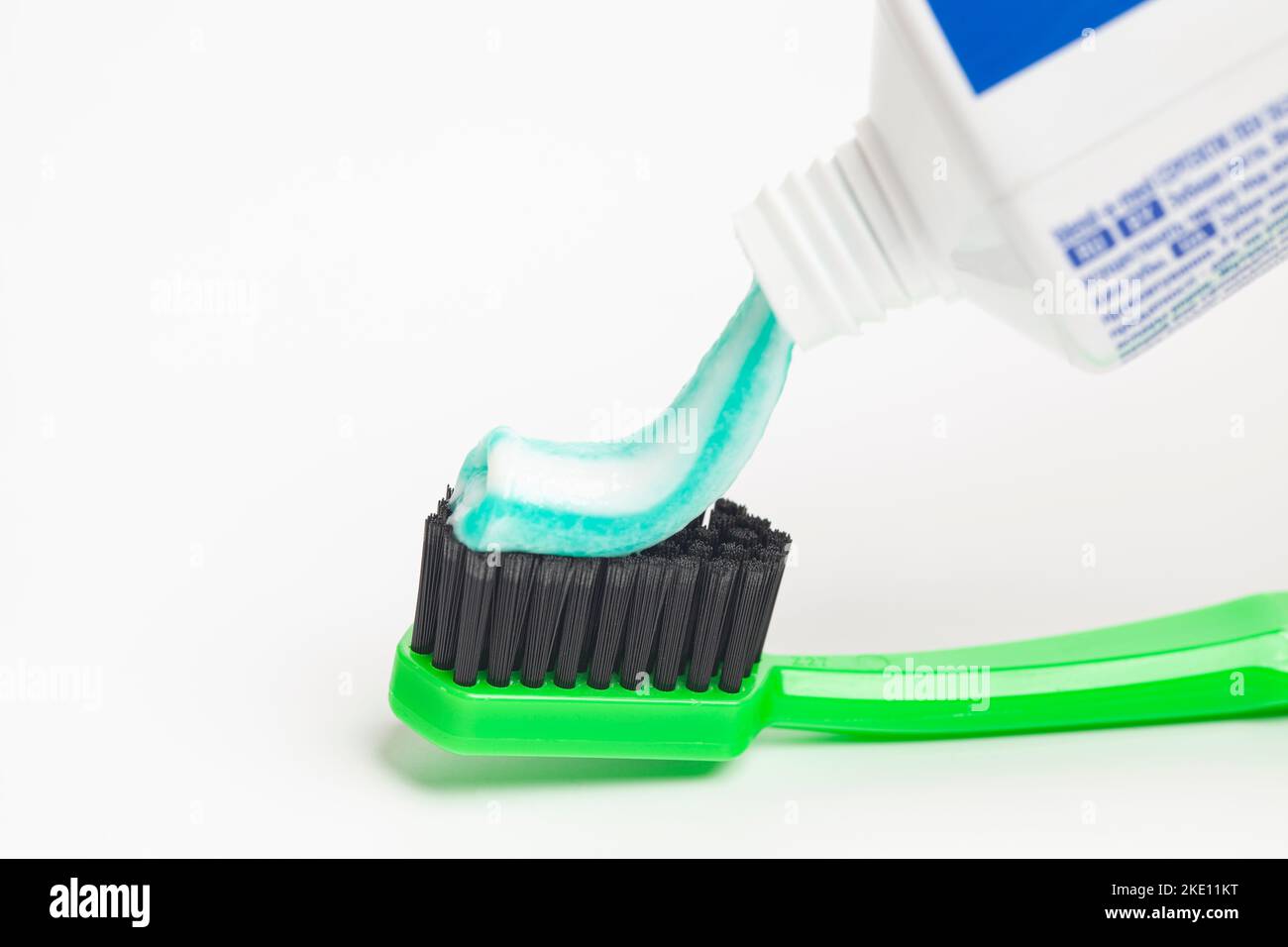 Close up of squeezing toothpaste on toothbrush on white background ...