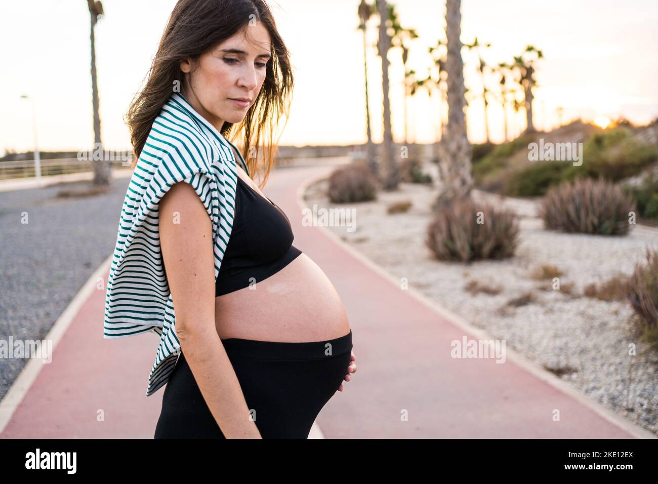 pregnant young woman with long brown hair wears sportswear and does ...