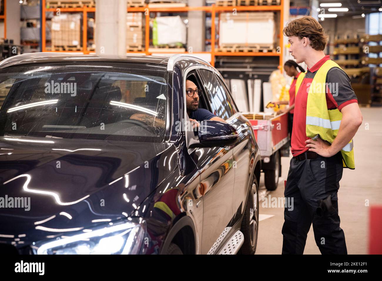 Side view of male sales staff with hand on hip talking to customer in ...